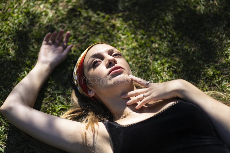 Overhead Portrait Of Blonde Woman Lying On The Grass With Lights And