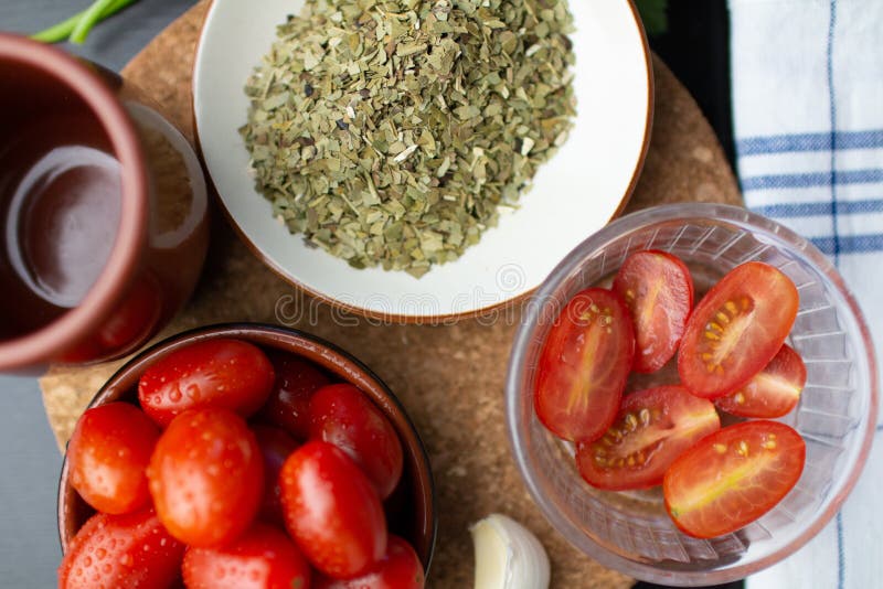 Overhead Shot of Bowls of Tomatoes Next To Condiments, Garlic and a Cup ...