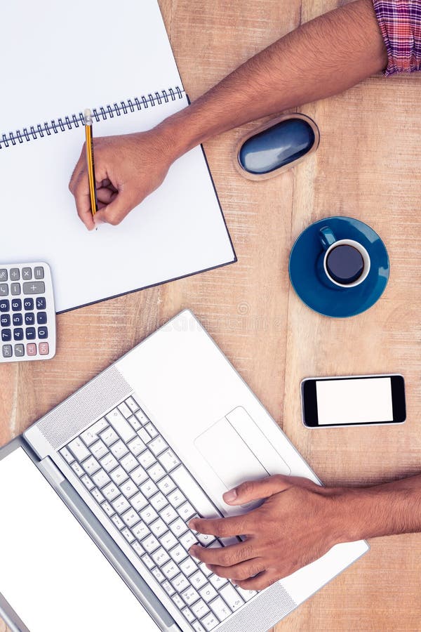 Overhead View of Businessman Writing on Book while Working on Laptop ...