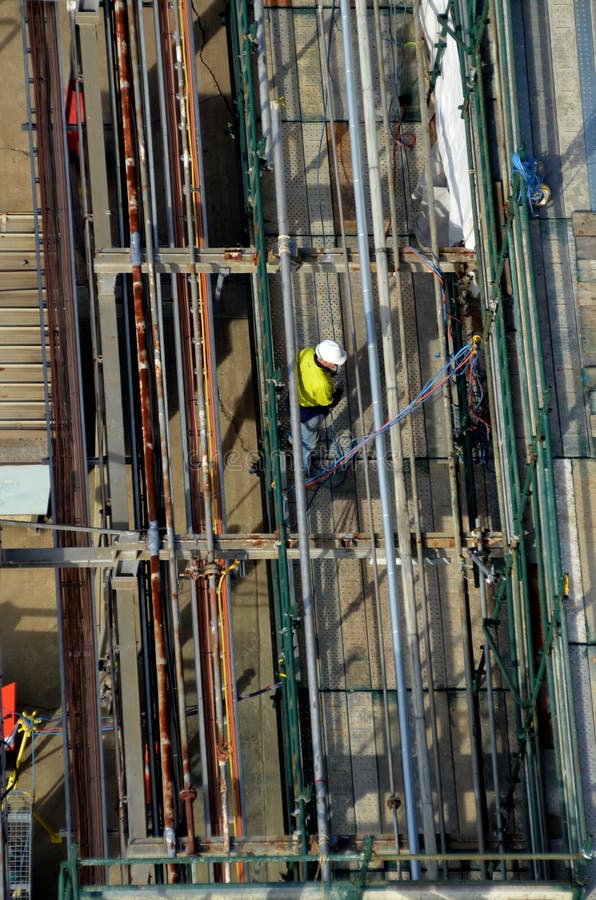 Overhead View of a Construction Worker Amongst Pipes and Scaffolding ...