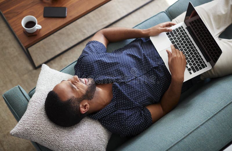 Overhead View of Man Lying on Sofa at Home Using Laptop Computer Stock ...