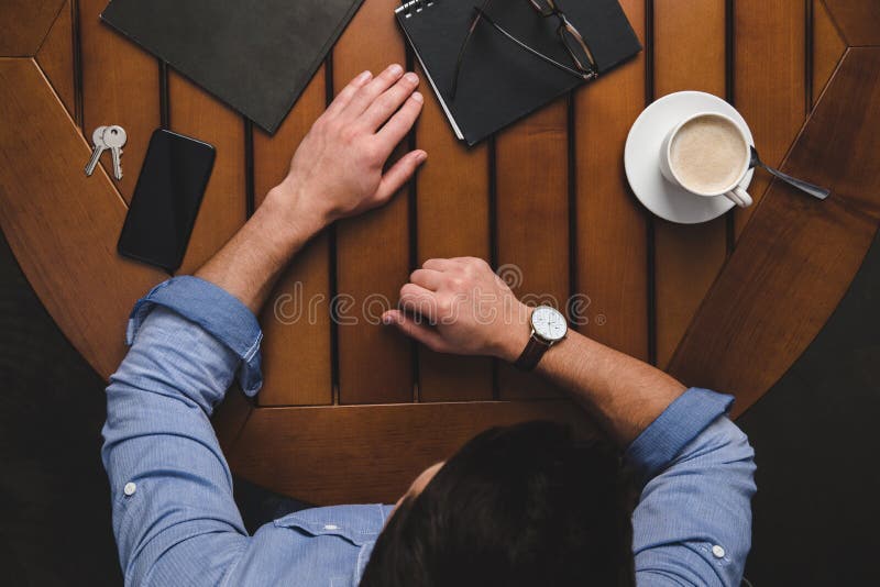 Overhead View of Man Sitting at Wooden Table with Notepads, Smartphone ...