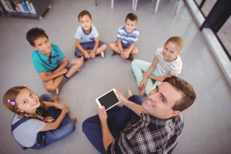 Overhead View of Teacher and Schoolkids Using Digital Tablet in Library ...