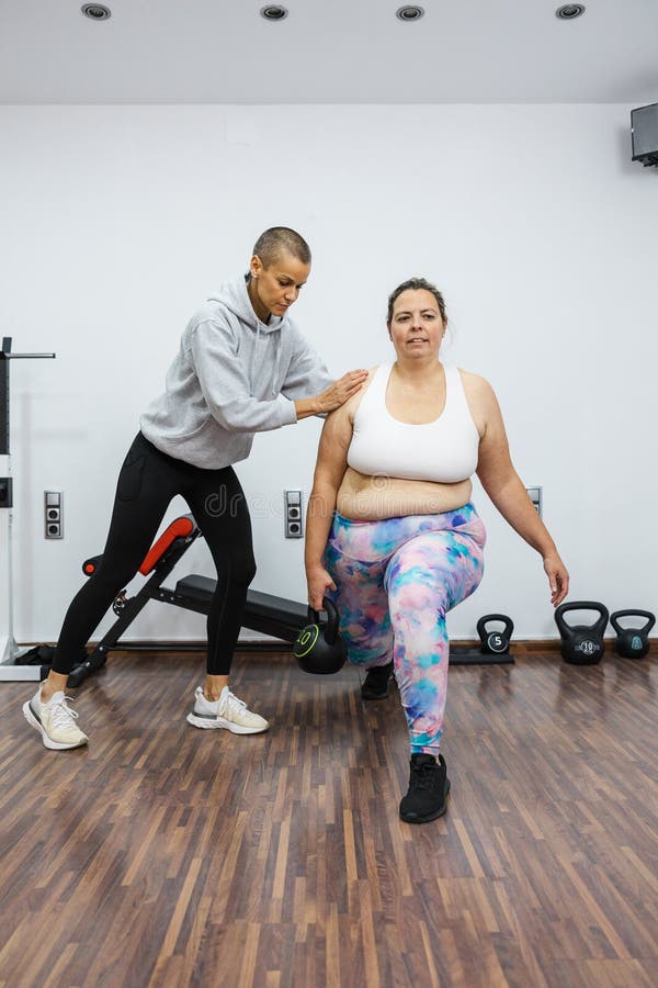 Personal Trainer Supporting Overweight Client during Kettlebell Workout ...