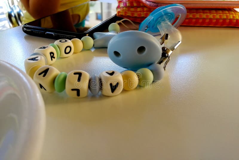 Pacifier with Chain and Name Written on a Table Next To Mobile Phone ...