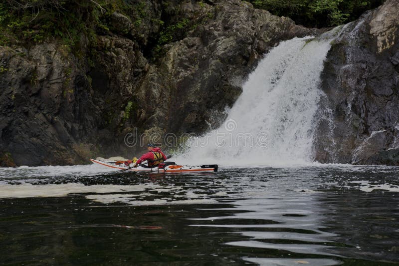 A Paddler Plays in the Current at the Bottom of a Waterfall in ...