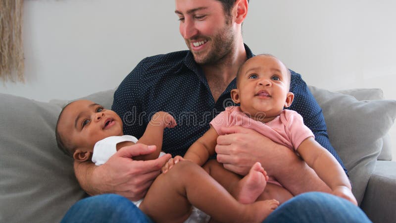 Padre Sentado En Sofá En Casa Cuidando a Hijo Y Hija Foto de archivo - Imagen de tenencia ...