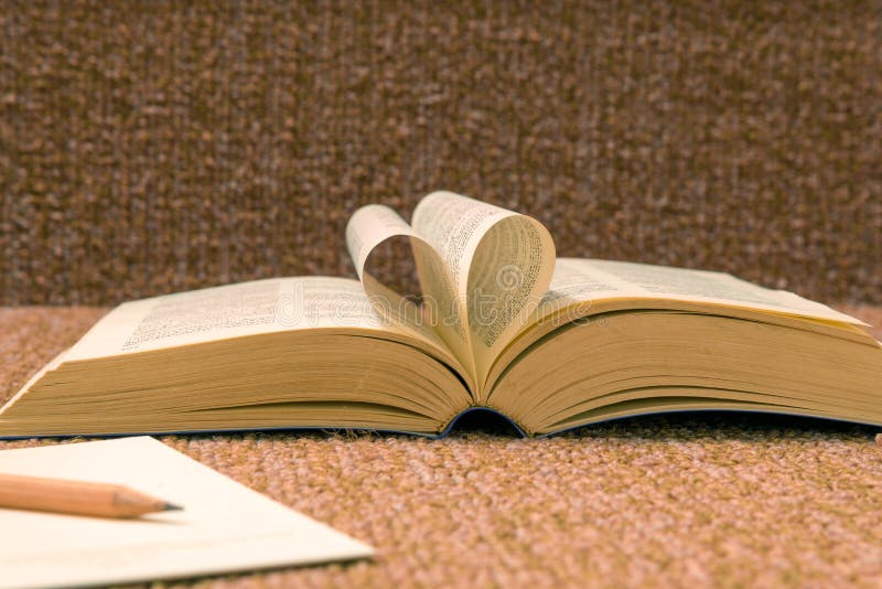Pages of Open Book Rolled in Heart Shape on Table Stock Image - Image ...