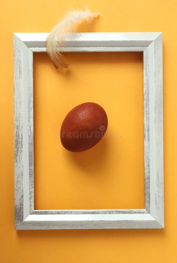 Painted Egg in a Gray Frame with Light Chicken Feathers on a Yellow ...