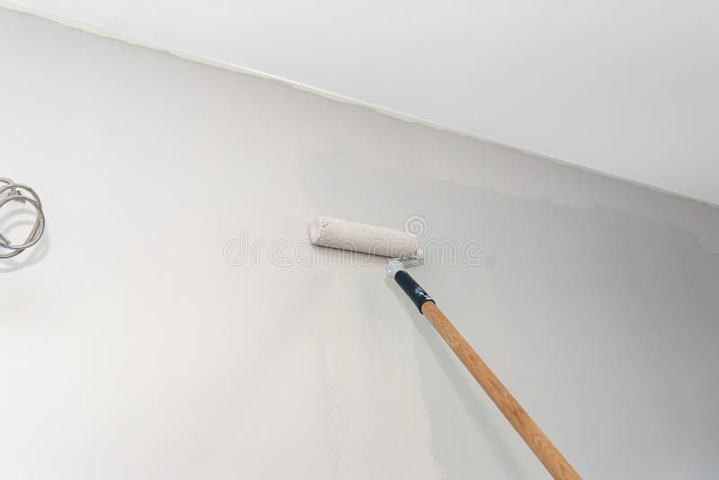 Painter Paints a Room in Beige Color Using a Paint Roller on an ...