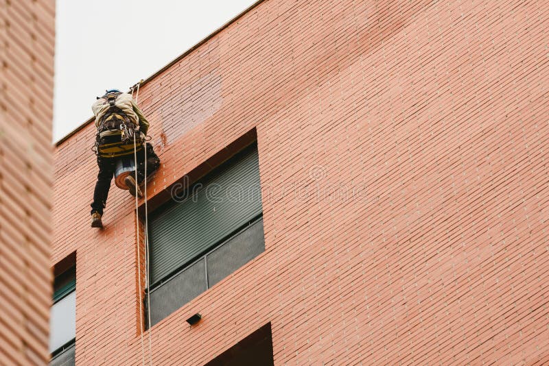 Painter Perched Hanging on the Walls of a Building with Ropes Stock ...
