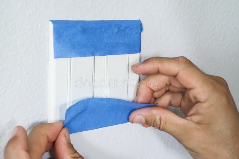 Painter Using Masking Blue Tape To Secure Light Switch. Preparation for ...