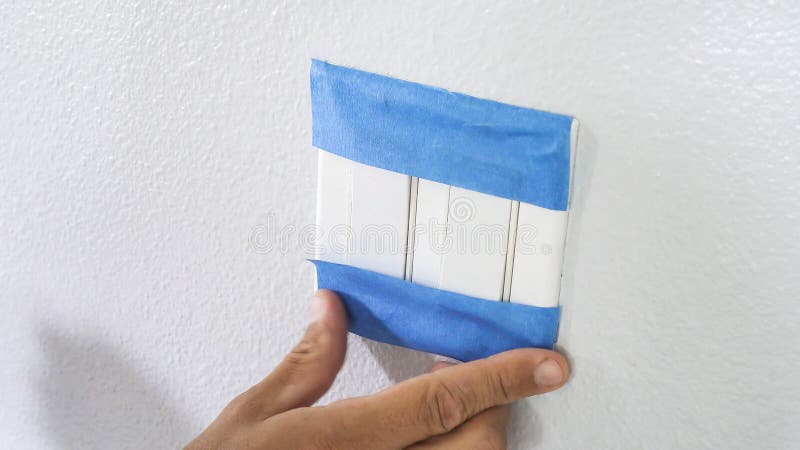 Painter Using Masking Blue Tape To Secure Light Switch. Preparation for ...