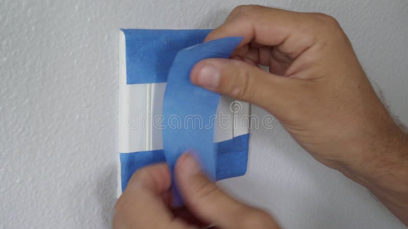 Painter Using Masking Blue Tape To Secure Light Switch. Preparation for ...