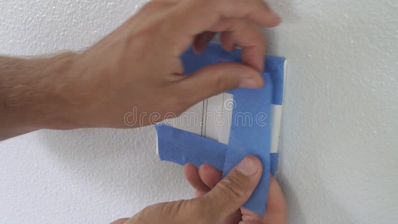 Painter Using Masking Blue Tape To Secure Light Switch. Preparation for ...