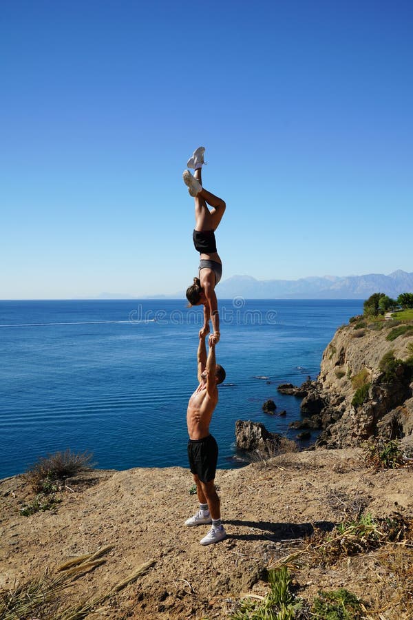 Pair Acrobatics. Handstand in Straight Hands on the Rocks by the Sea ...