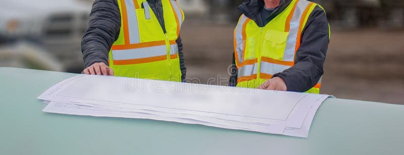 A Pair of Construction Engineers are Reviewing Construction Drawings ...