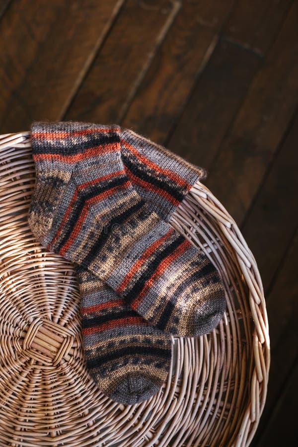A Pair of Hand Knitted Multi-colored Socks on a Pad. Dark Rustic Wooden ...