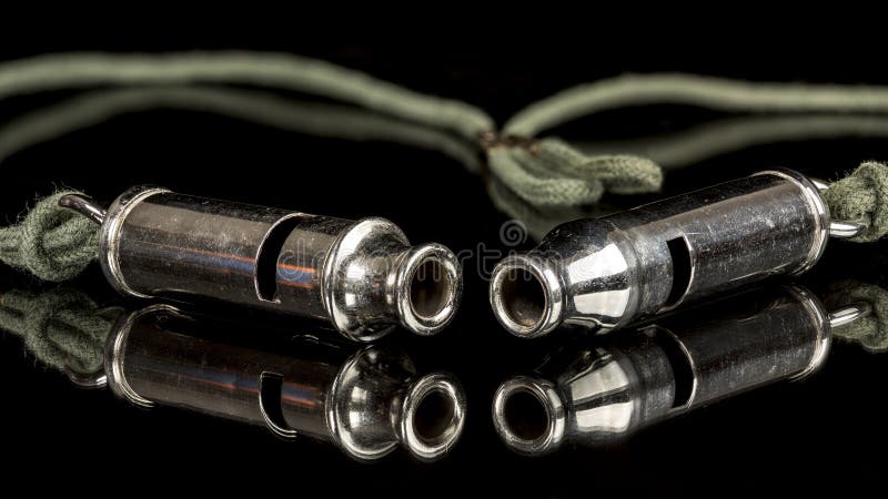Pair of Metal Whistles with a Green Strap on a Reflective Surface Stock ...