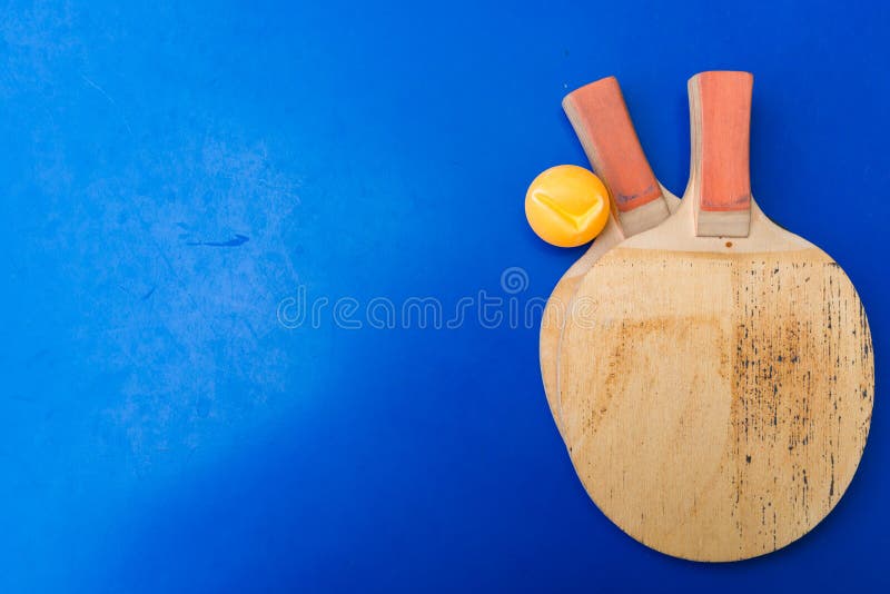 Pair of Old Pingpong Rackets and a Dented Ball on Blue Pingpong Table ...
