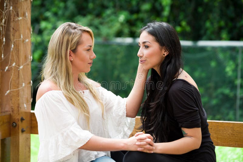 A Pair Of Proud Lesbian Sitting In Outdoors Looking At Each Other And