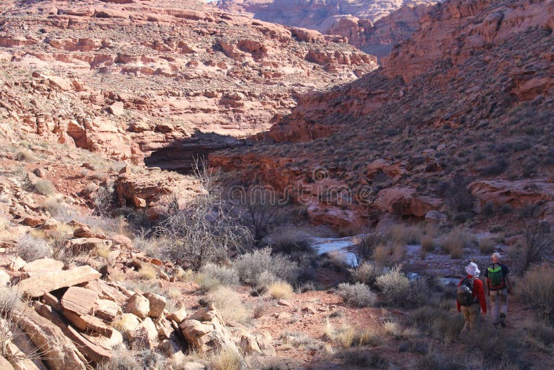 Pair of Tourists Exploring a Dry Canyon with Rocky Cliffs Shading Them ...
