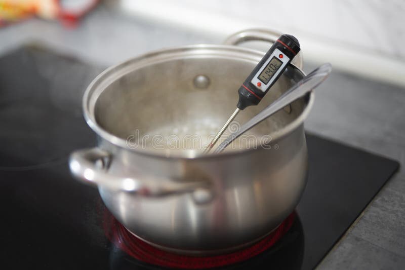 A Pan on an Electric Stove and a Thermometer Measures the Temperature ...