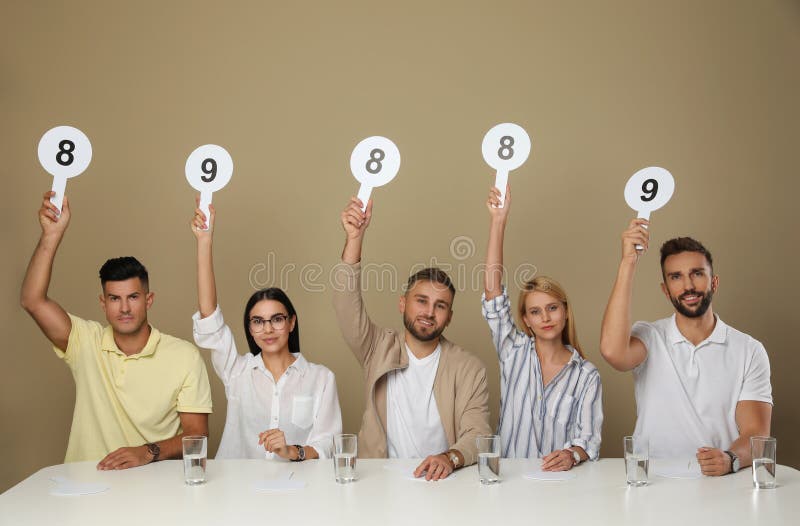 Panel of Judges Holding Different Score Signs at Table on Beige ...