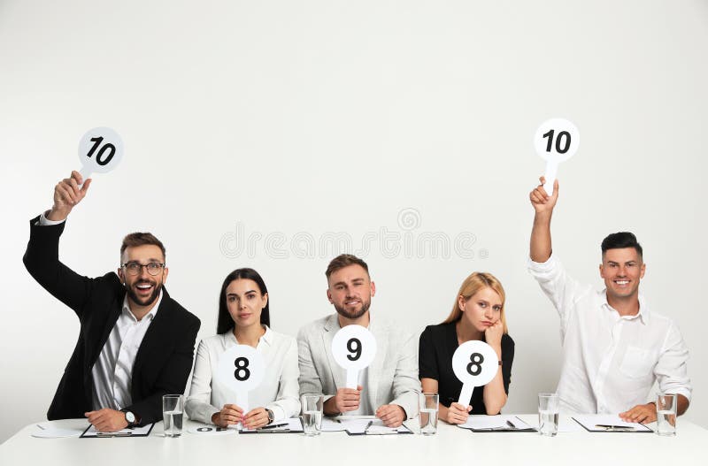 Panel of Judges Holding Signs with Highest Score at Table on White ...