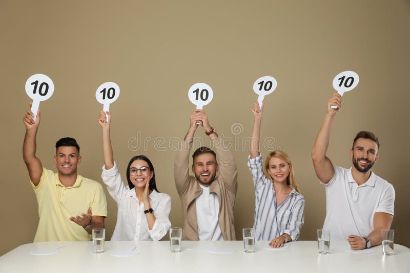 Panel of Judges Holding Signs with Highest Score at Table on Beige ...