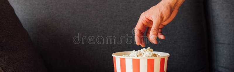 Crop of Man Reaching Popcorn in Bucket Stock Image - Image of sofa ...