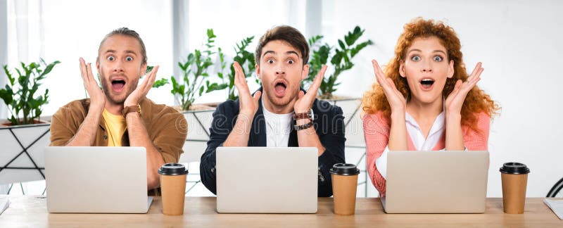 Shot of Three Shocked Friends Sitting at Table and Looking at Camera ...