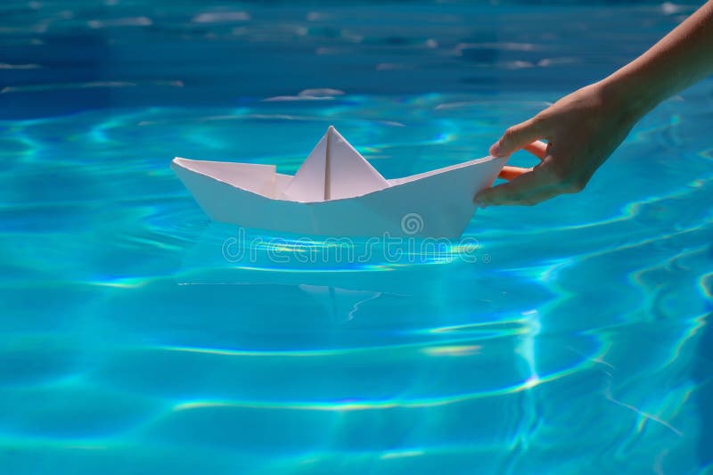 Paper Boat Sailing on Water Causing Waves and Ripples. Hand Putting a ...
