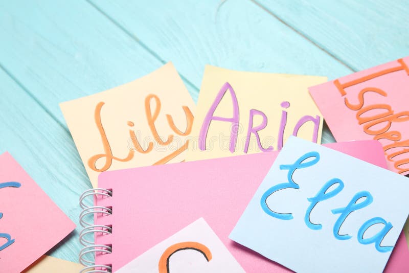 Paper Notes with Different Baby Names and Notebook on Light Blue Wooden ...