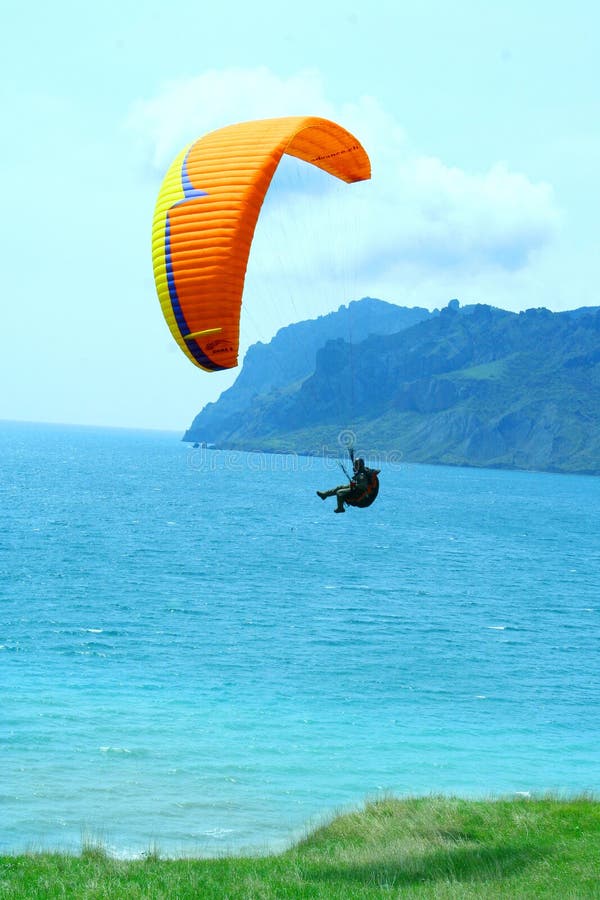Paraglider in a Black Gondola on a Red Parachute Flies in a Clear Blue ...