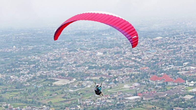 Paraglider Pilot Flying High in Blue Sky with Village and Mountain View ...