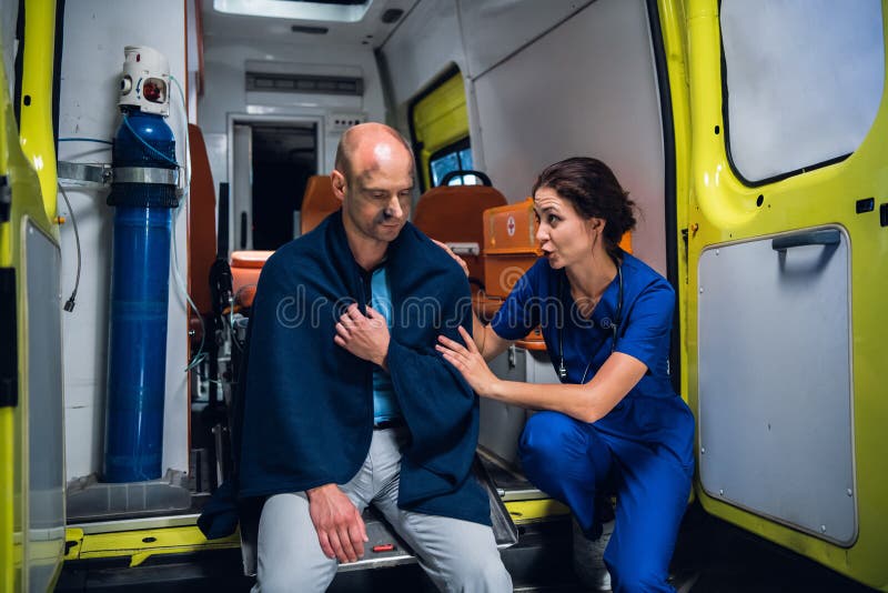 A Paramedic Puts On An Oxygen Mask On An Unconscious Woman Lying On
