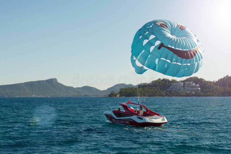 Parasailing, a Red and White Boat Pulls a Blue Parachute with a Smiley ...