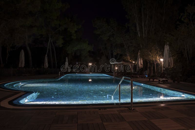 Parasols and Deck Chairs Arranged by Illuminated Swimming Pool at Night ...