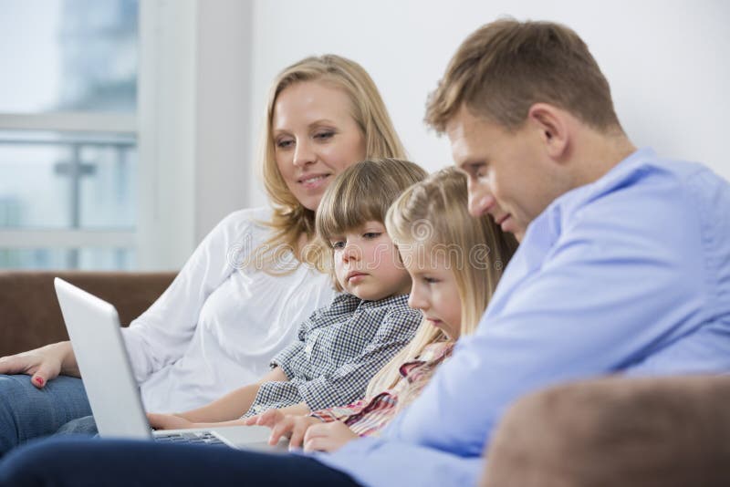 Parents with Children Using Laptop on Sofa at Home Stock Image - Image ...
