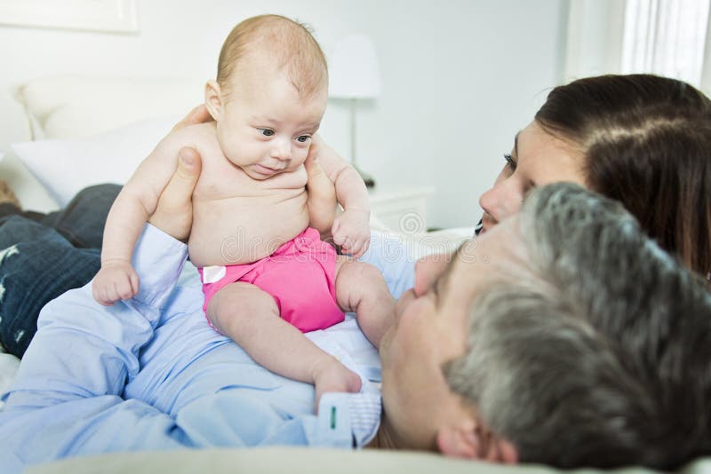 Parents Cuddling Newborn Baby in Bed at Home Stock Image - Image of ...