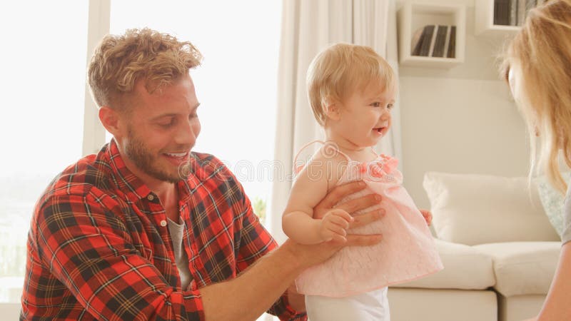 Parents Helping Baby Daughter To Take First Steps at Home Stock Image ...