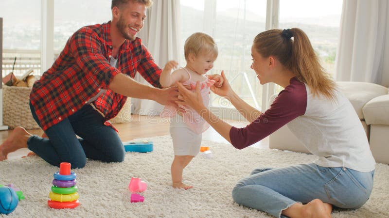Parents Helping Baby Daughter To Take First Steps at Home Stock Photo - Image of girl, father ...