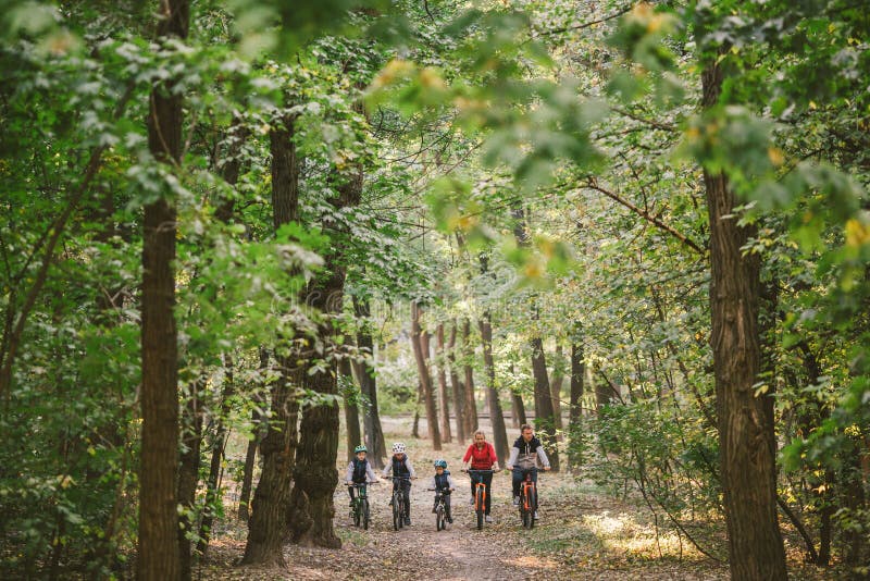 Parents and Kids Cycling on Forest Trail. Young Family Cycling in ... Parents and Kids Cycling on Forest Trail. Young Family Cycling in ...