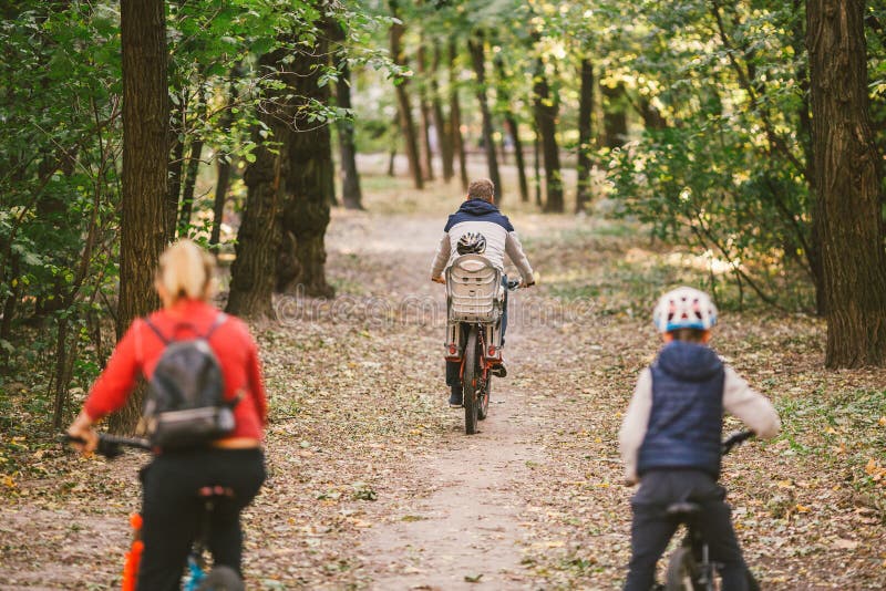 Parents and Kids Cycling on Forest Trail. Young Family Cycling in ... Parents and Kids Cycling on Forest Trail. Young Family Cycling in ...