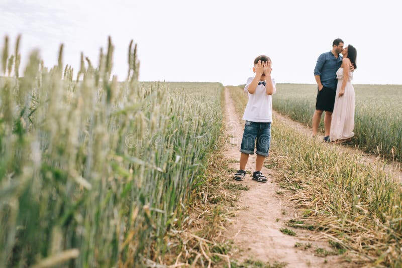 Parents Kissing and Son Covering Eyes on Path Stock Photo - Image of ...