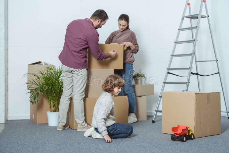 Parents Packing Boxes and Son Playing on Floor Stock Photo - Image of ...