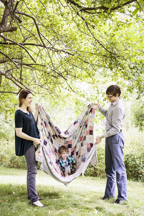 Parents Playing with Child in Blanket Stock Image - Image of quilt ...