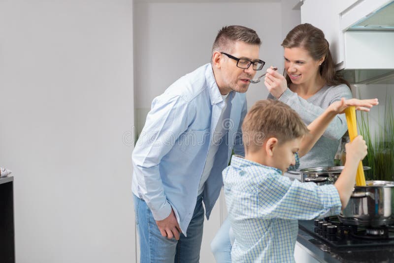 Parents Tasting Food while Son Preparing Food in Kitchen Stock Photo ...