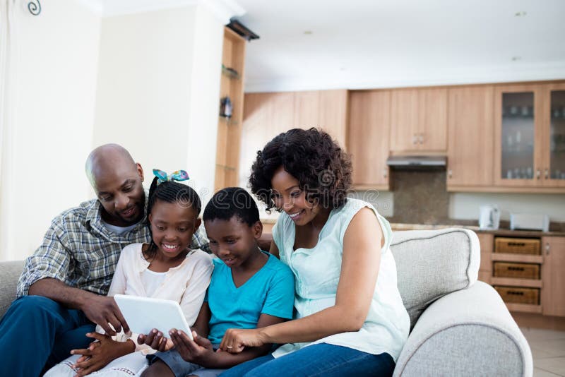 Parents and Their Children Using Digital Tablet in Living Room Stock ...